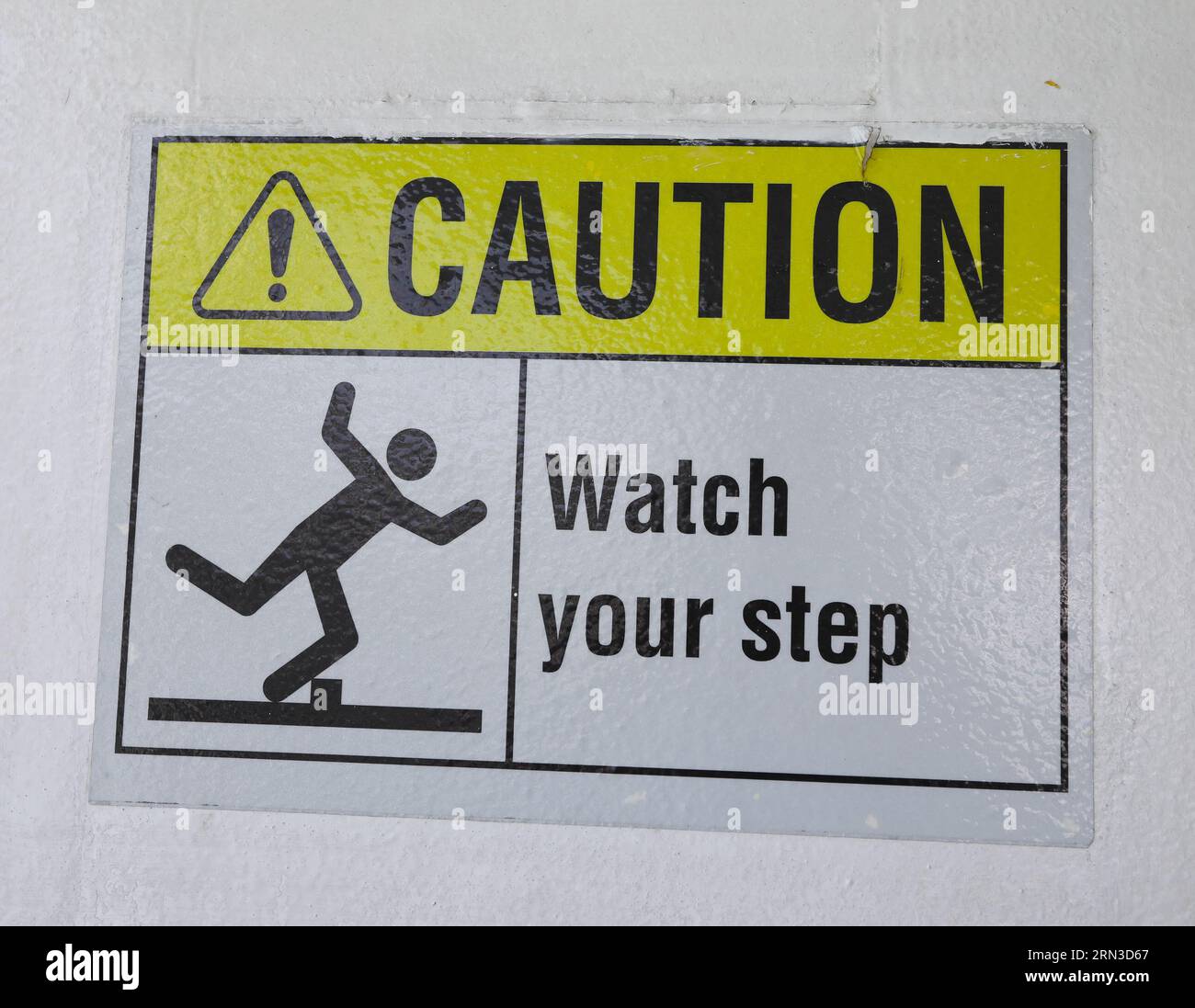 Yellow and black warning sign on stairs stating "Watch your Step ...
