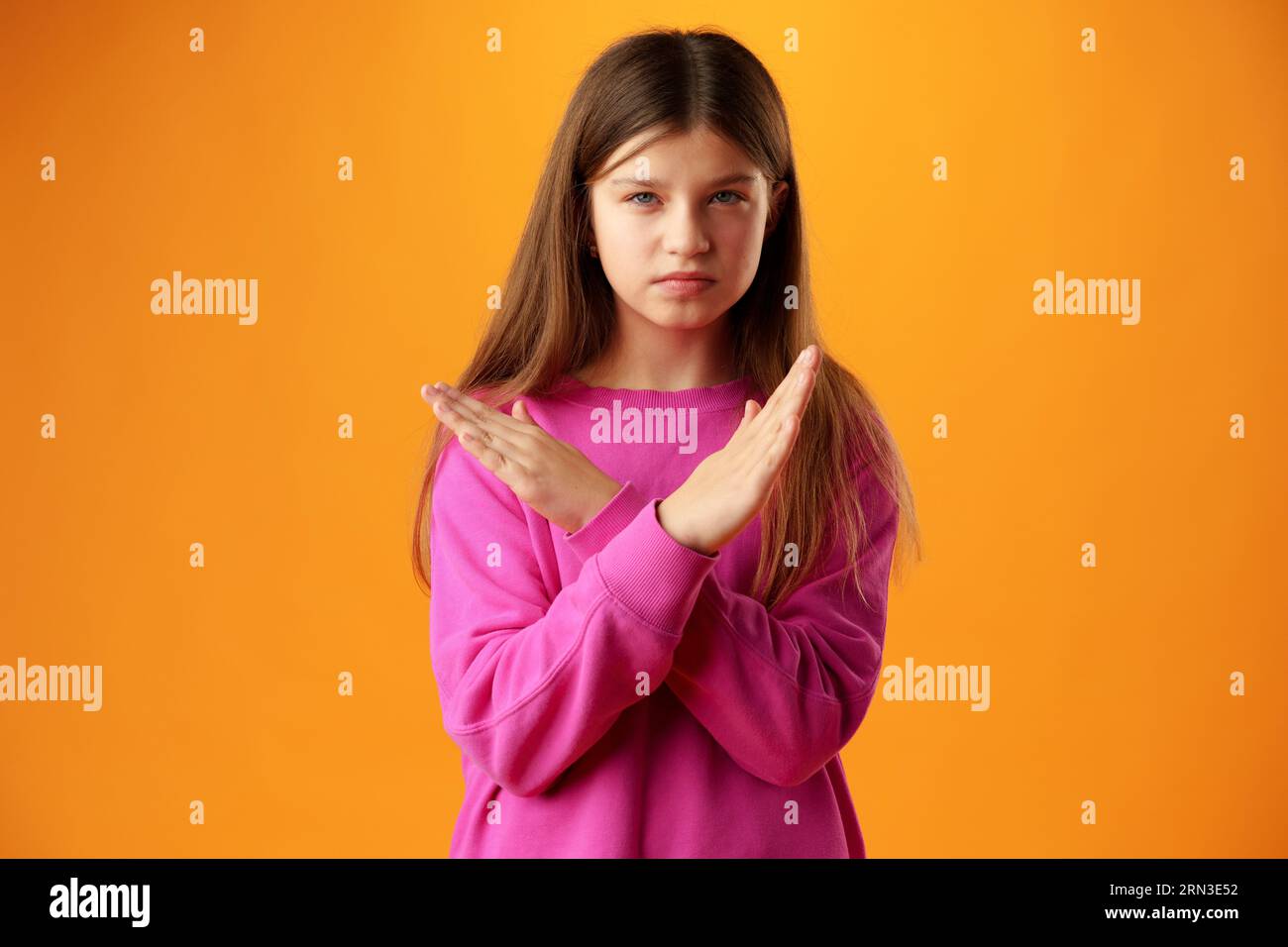 Teen girl shows cross hands gesture, rejecting something over yellow ...