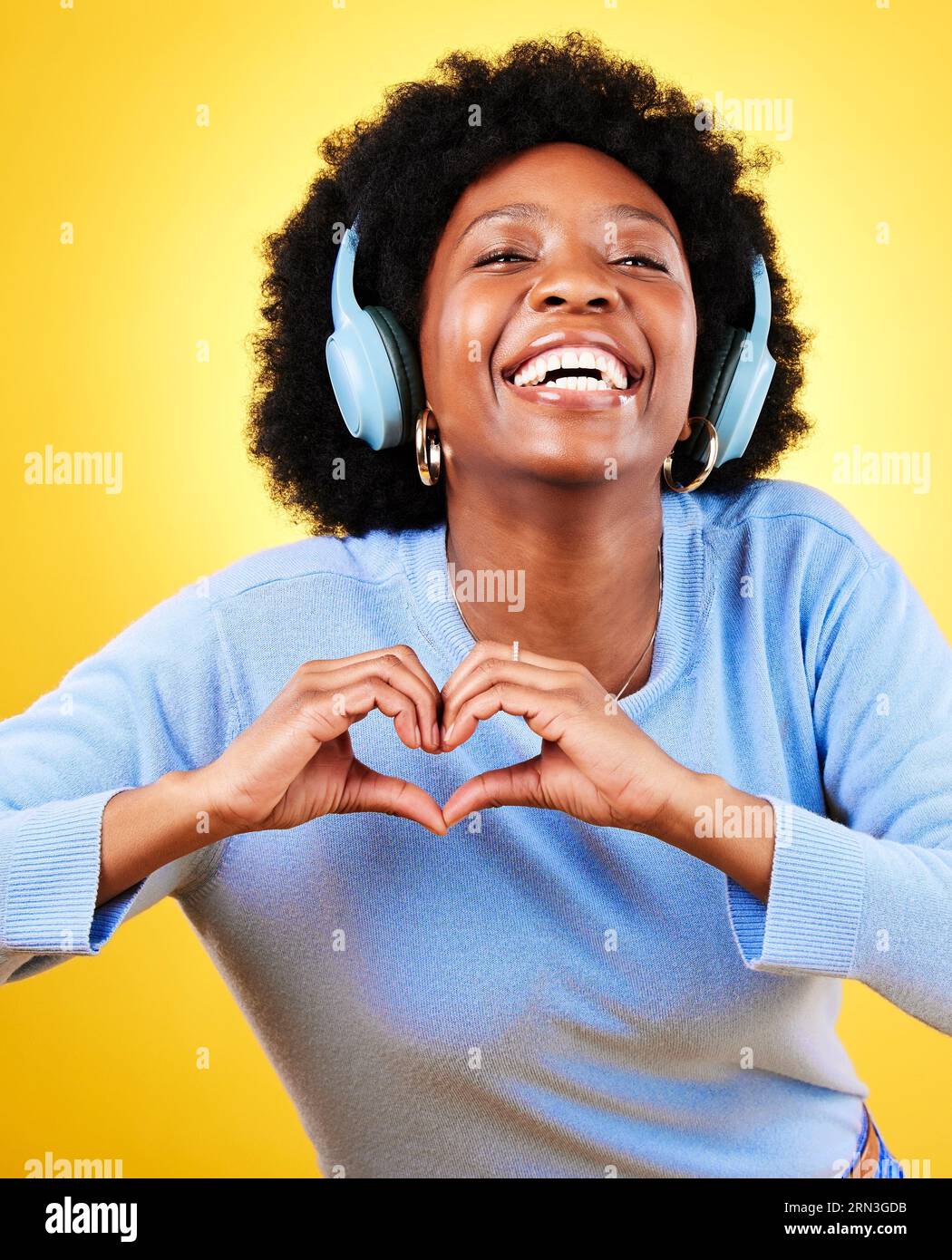 Portrait, heart hands and headphones of woman in studio for sign ...