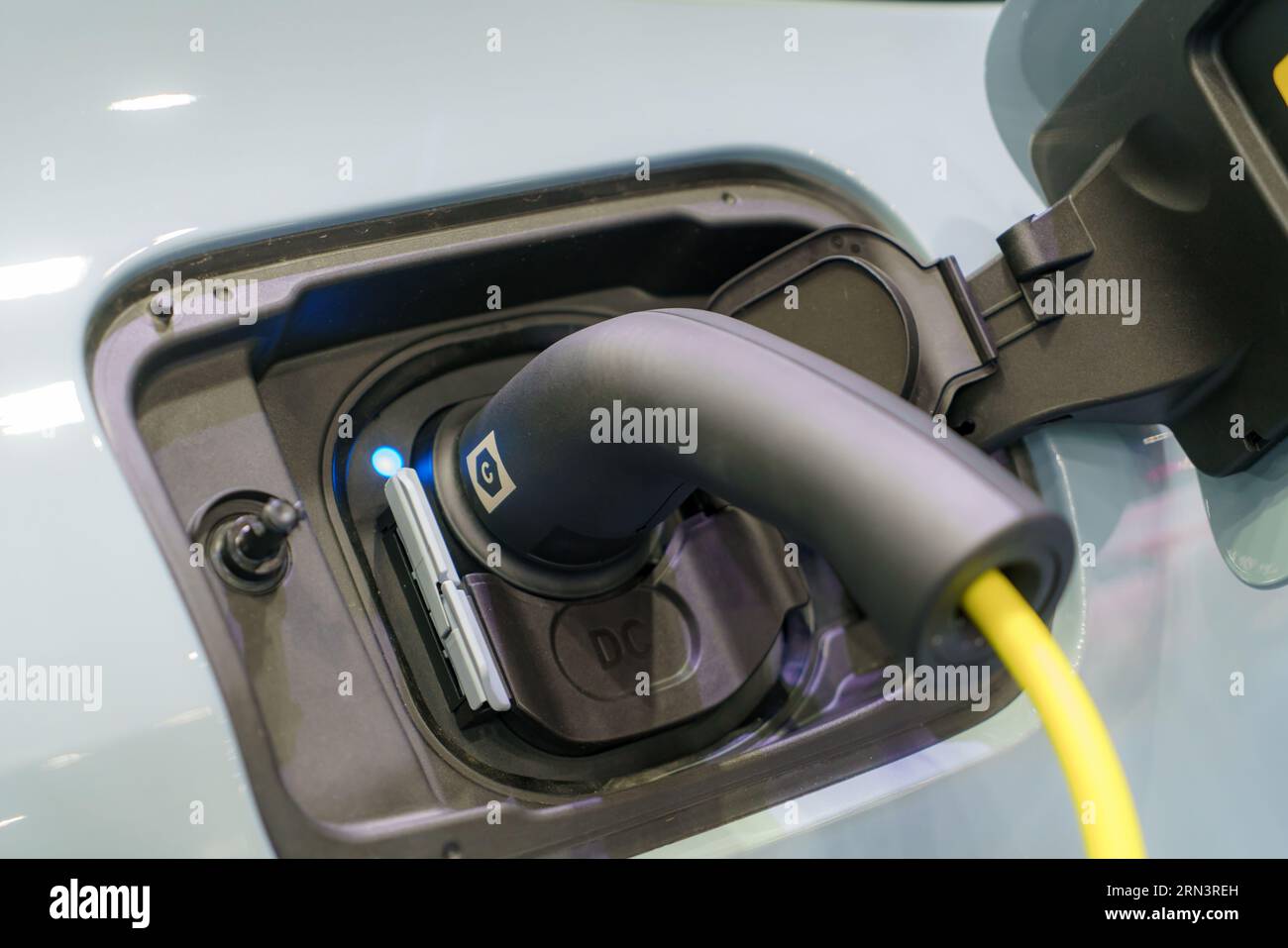 EV car rests at a charging station, power cable connected, embodying ...