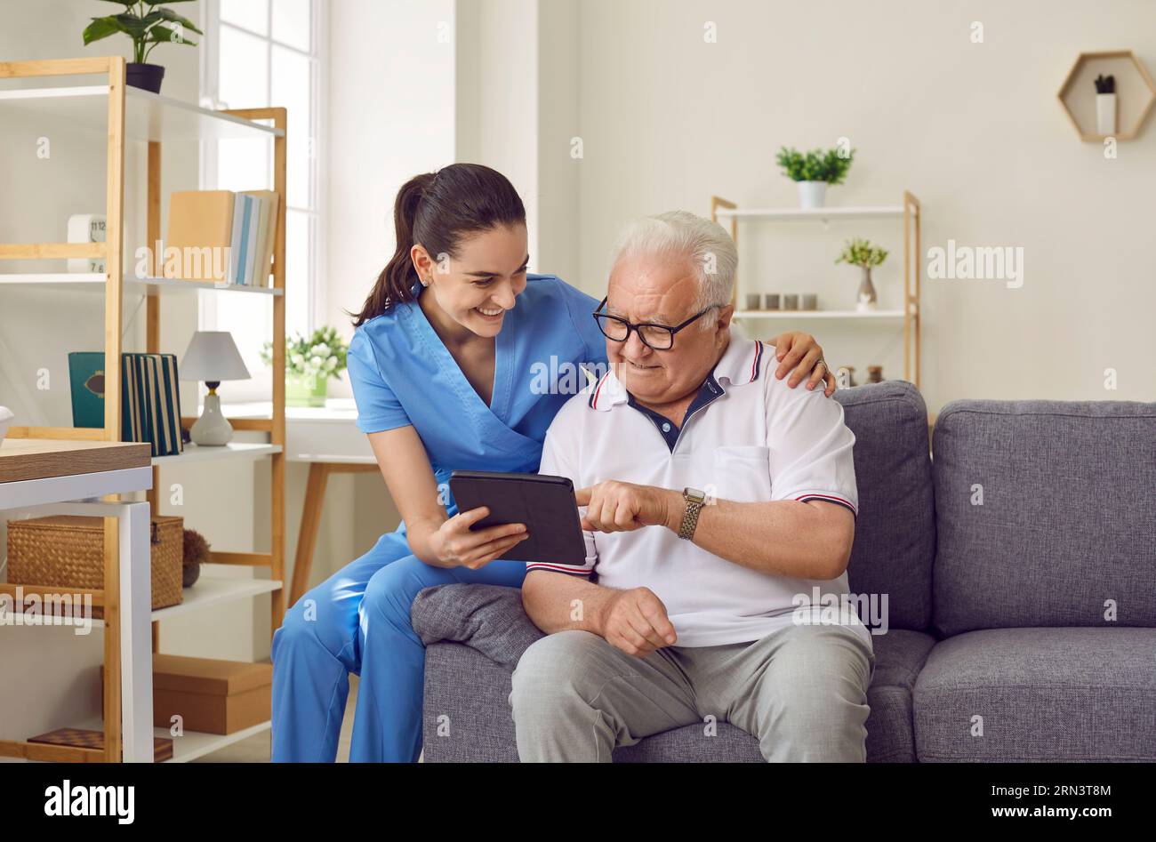 Nurse shows older male patient digital tablet with new software ...