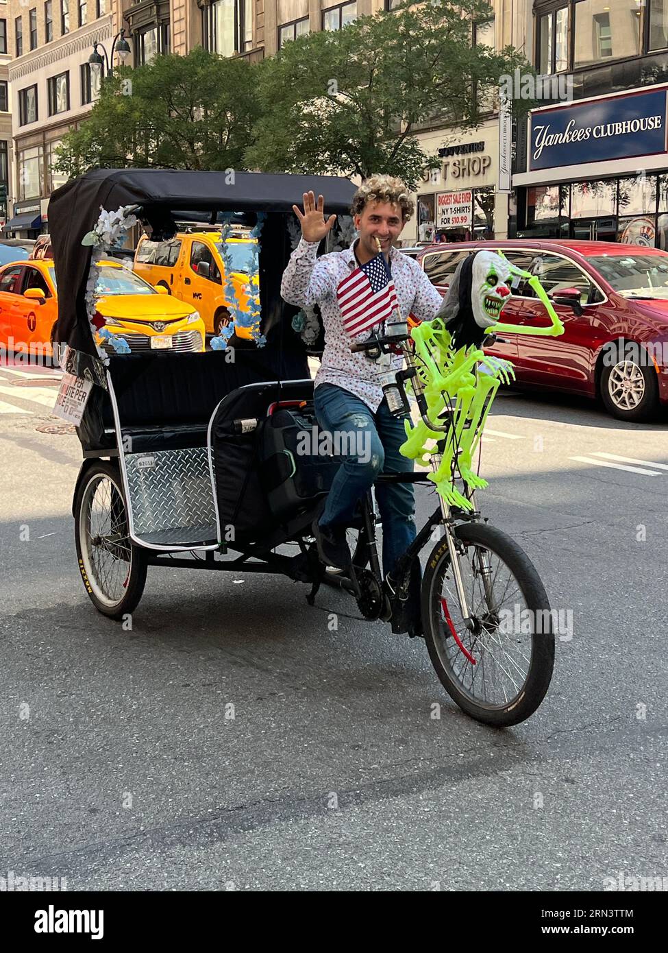 Pedicab driver gives a friendly wave as he passes by on 5th Avenue in ...