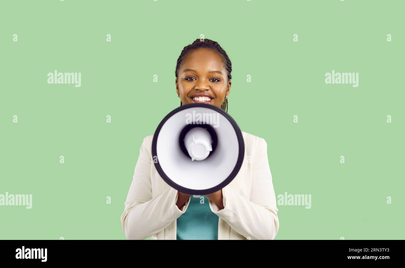 Smiling dark skinned woman making announcement with loudspeaker ...