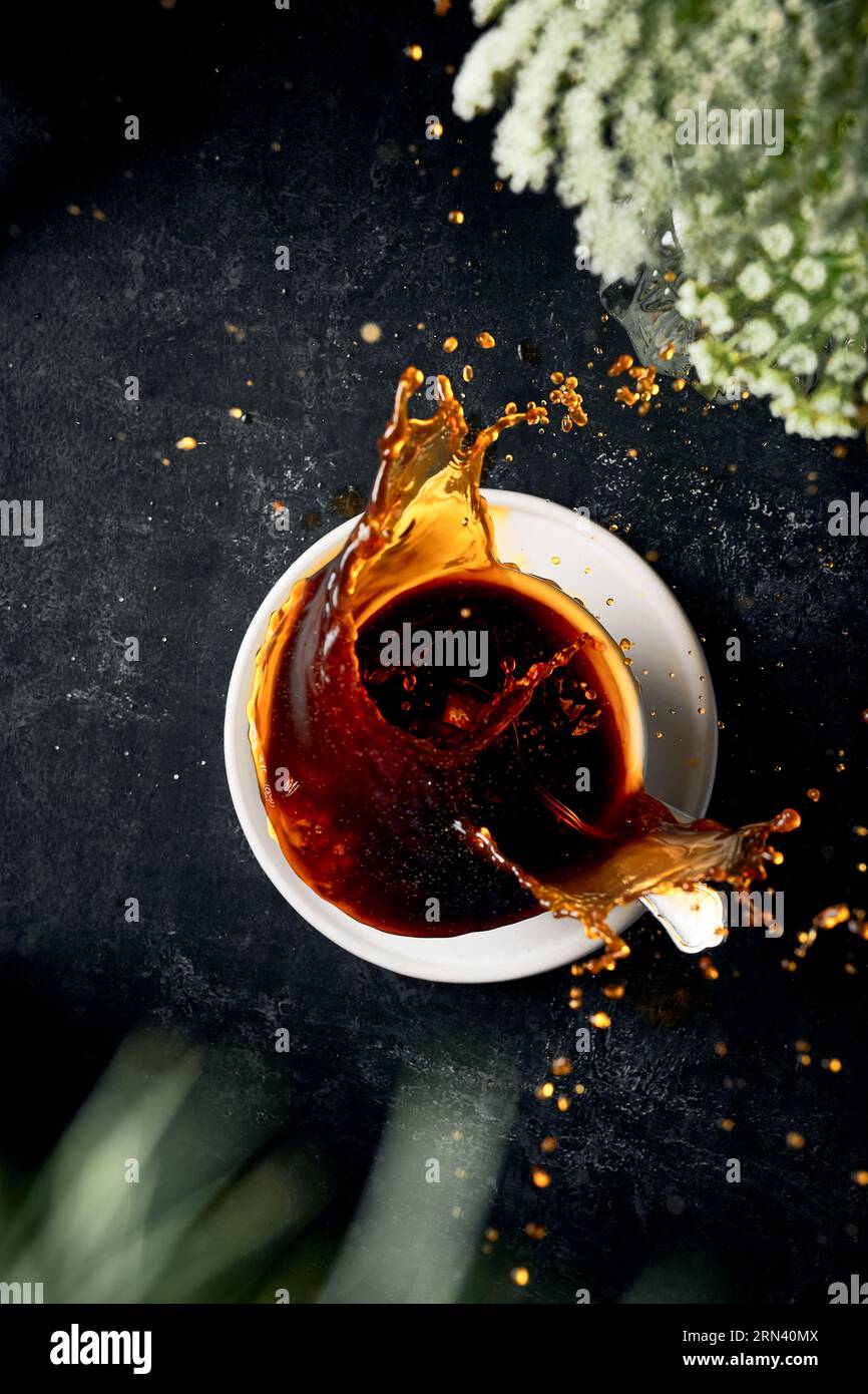 Top view vertical picture of splash in the cup of coffee. Black coffee ...