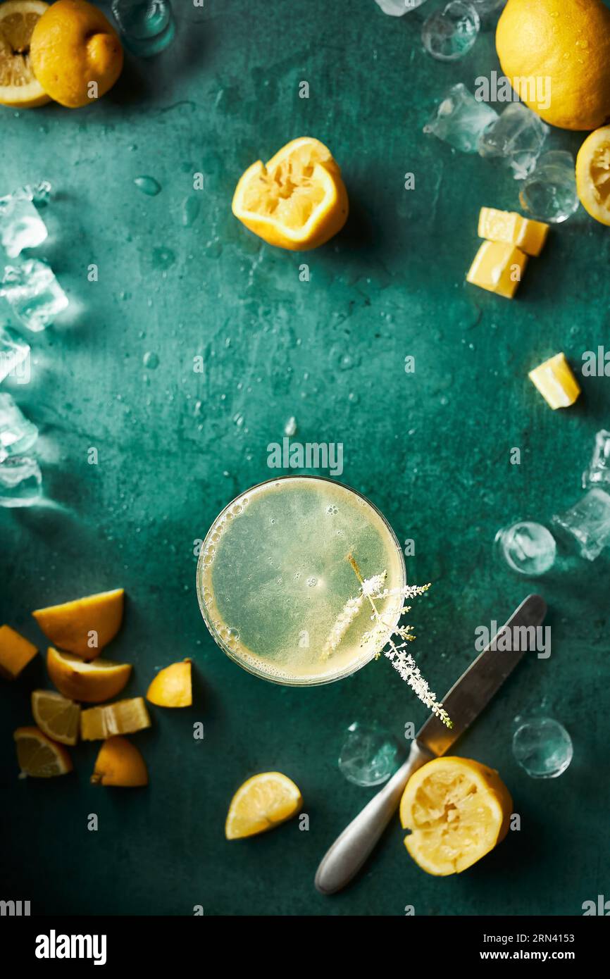 Citrus cocktail on a teal background surrounded by ice, splashes and ...
