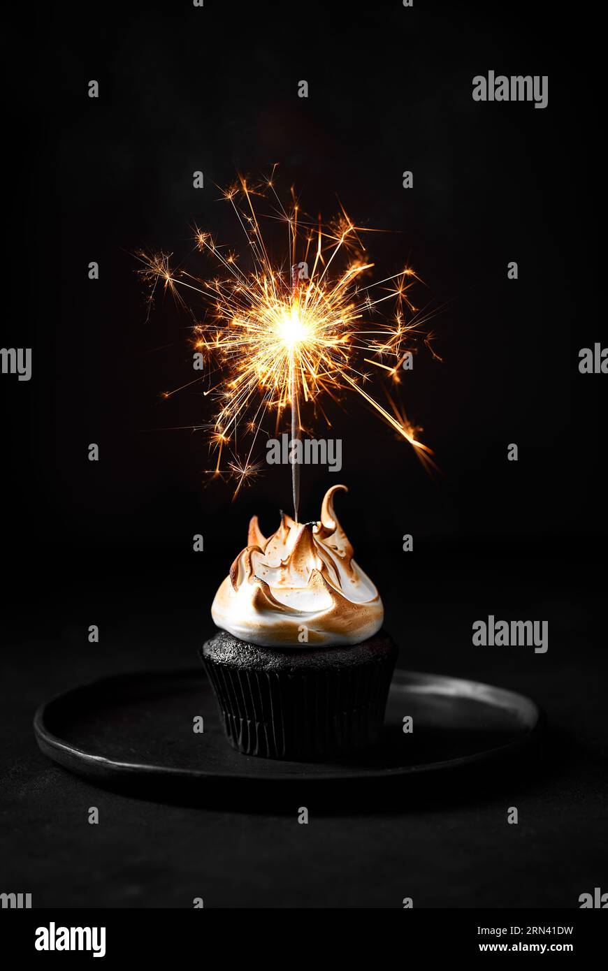 Single chocolate cupcake with meringue frosting. Sparkler in the ...