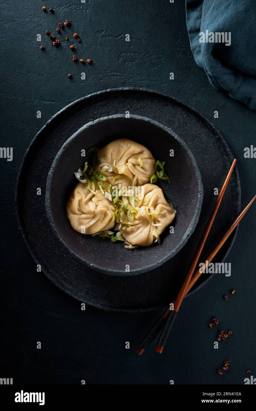 Ready to eat dim sum in the bowl garnished with herbs. Black ceramic ...