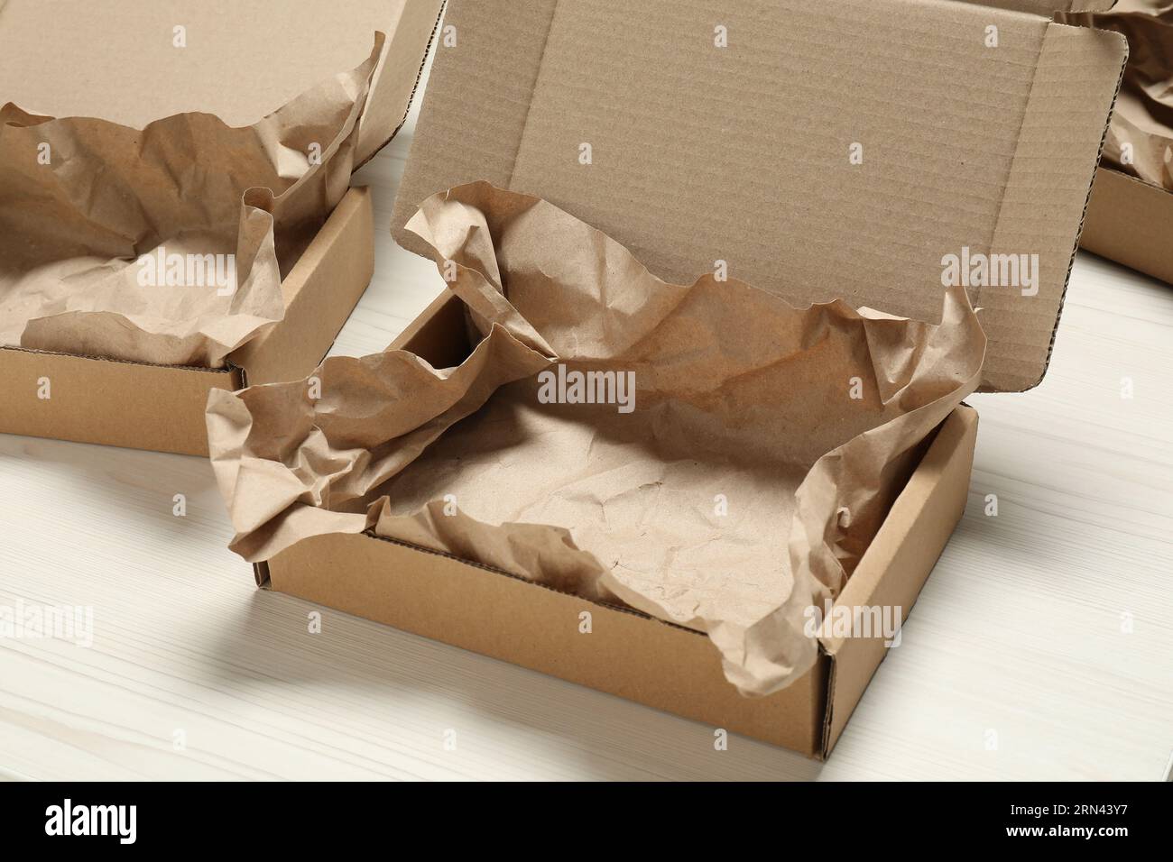 Open cardboard boxes with crumpled paper on white wooden floor Stock ...
