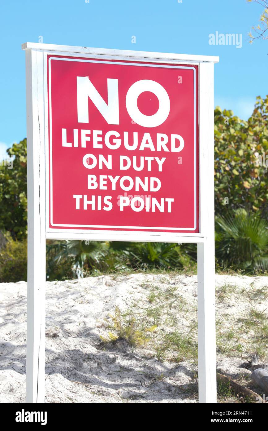 A sign on the beach that says "No lifeguards on duty Stock Photo - Alamy