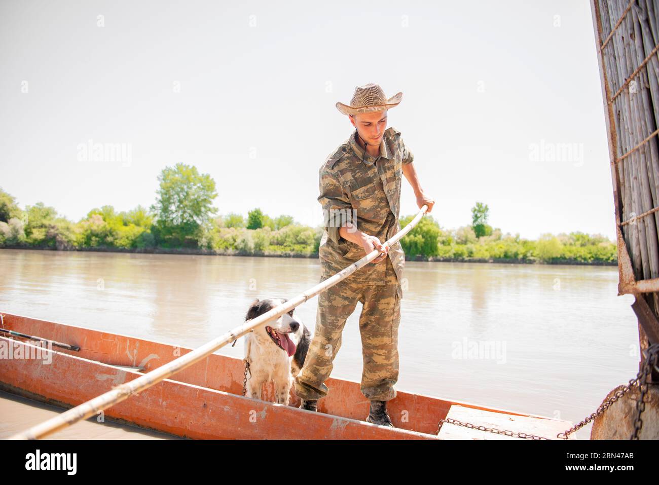 Active male fisher with dog sailing from shore in old boat, going ...