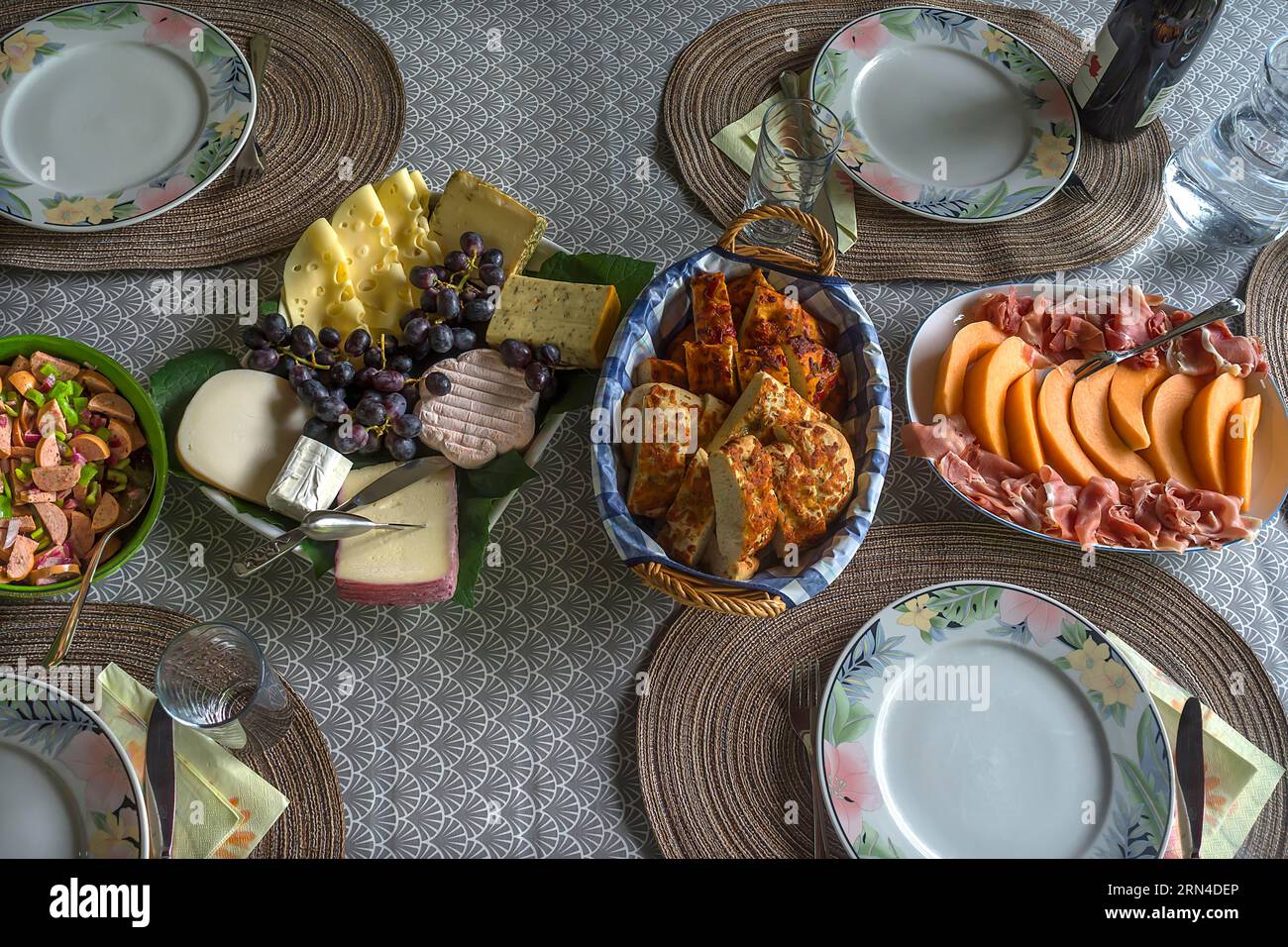 Set table with cold buffet, sausage salad, cheese with grapes, melon ...
