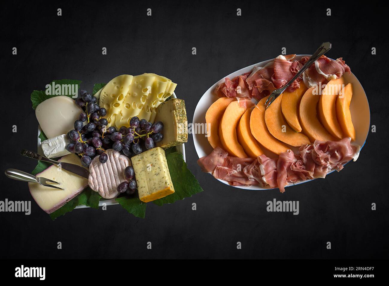 Cold buffet platters with melon, ham and cheese on a dark background ...