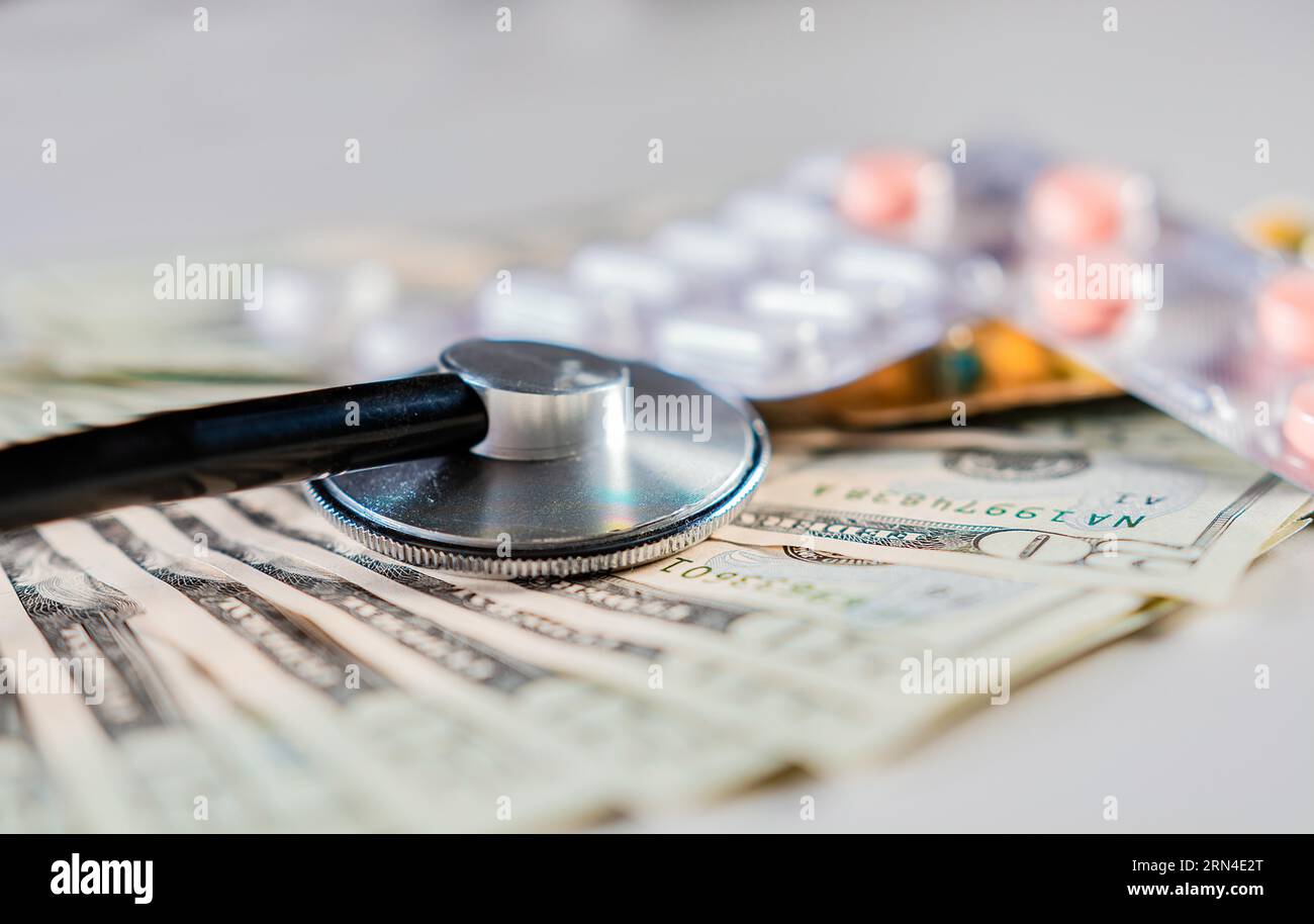 Close up of stethoscope with pills on dollar bills. High cost of ...