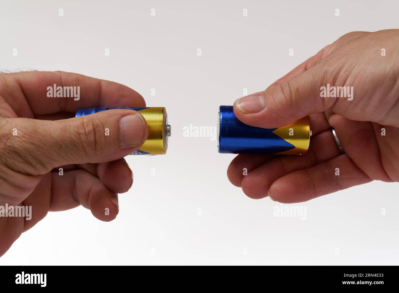 Man's hand and woman's hand hold a battery with opposite poles on a ...
