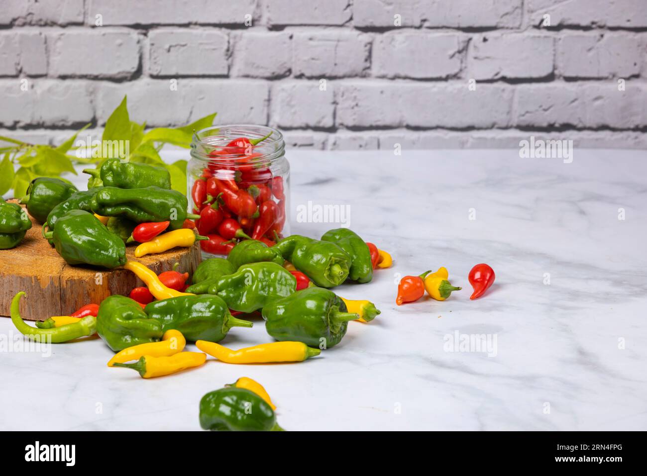 Various peppers in red, yellow and green, on and next to wooden disc ...
