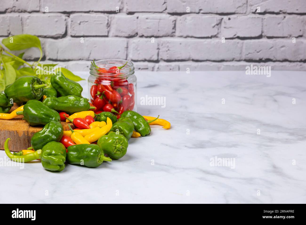 Various peppers in red, yellow and green, on and next to wooden disc ...