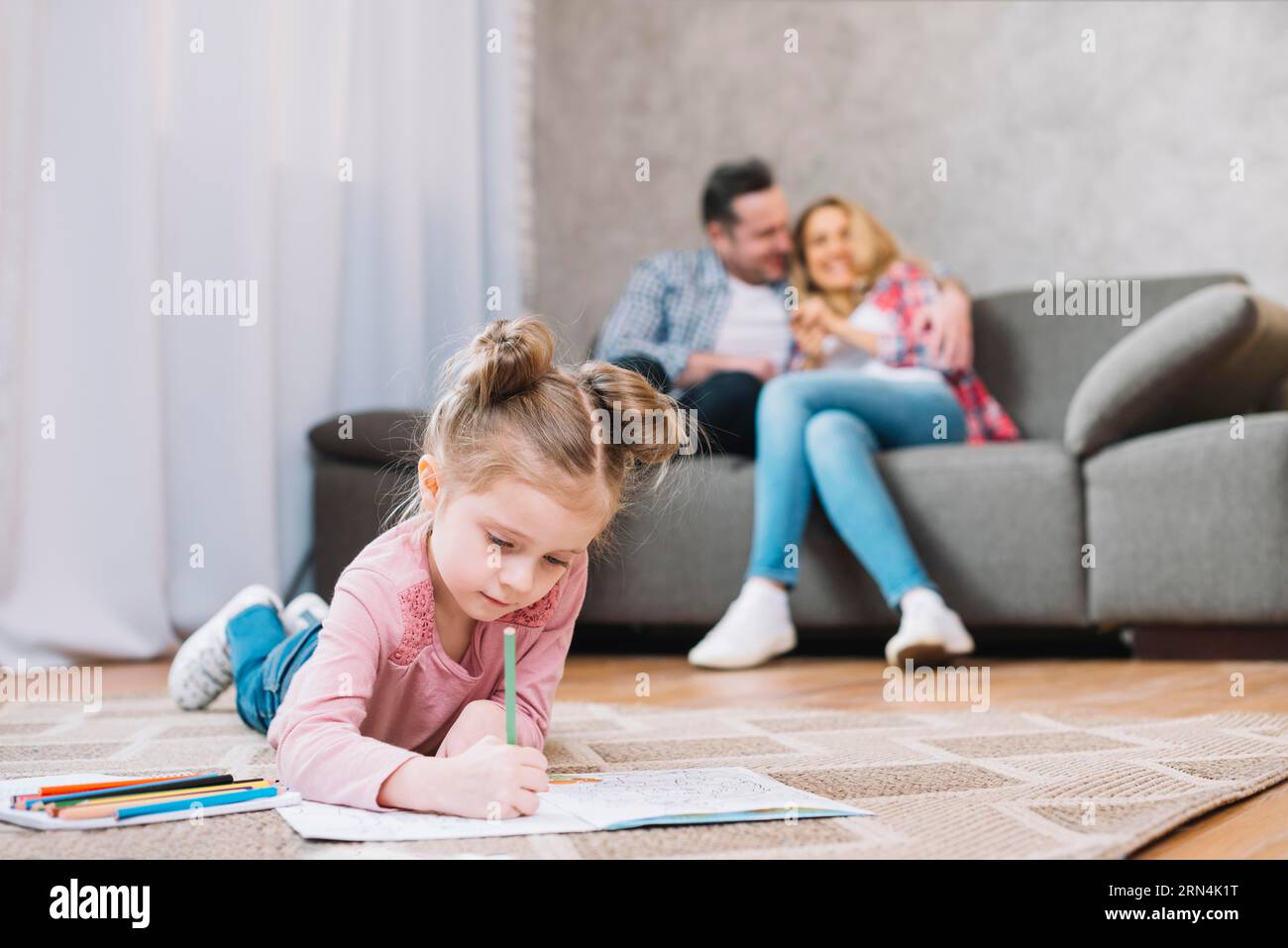 Little girl drawing book lying floor while her loving parents sitting ...