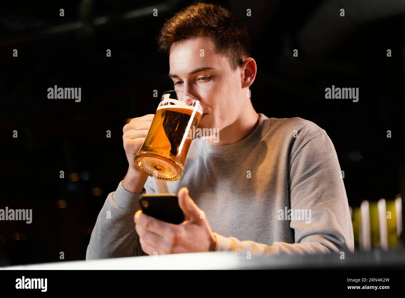 Medium shot man with phone beer mug Stock Photo - Alamy