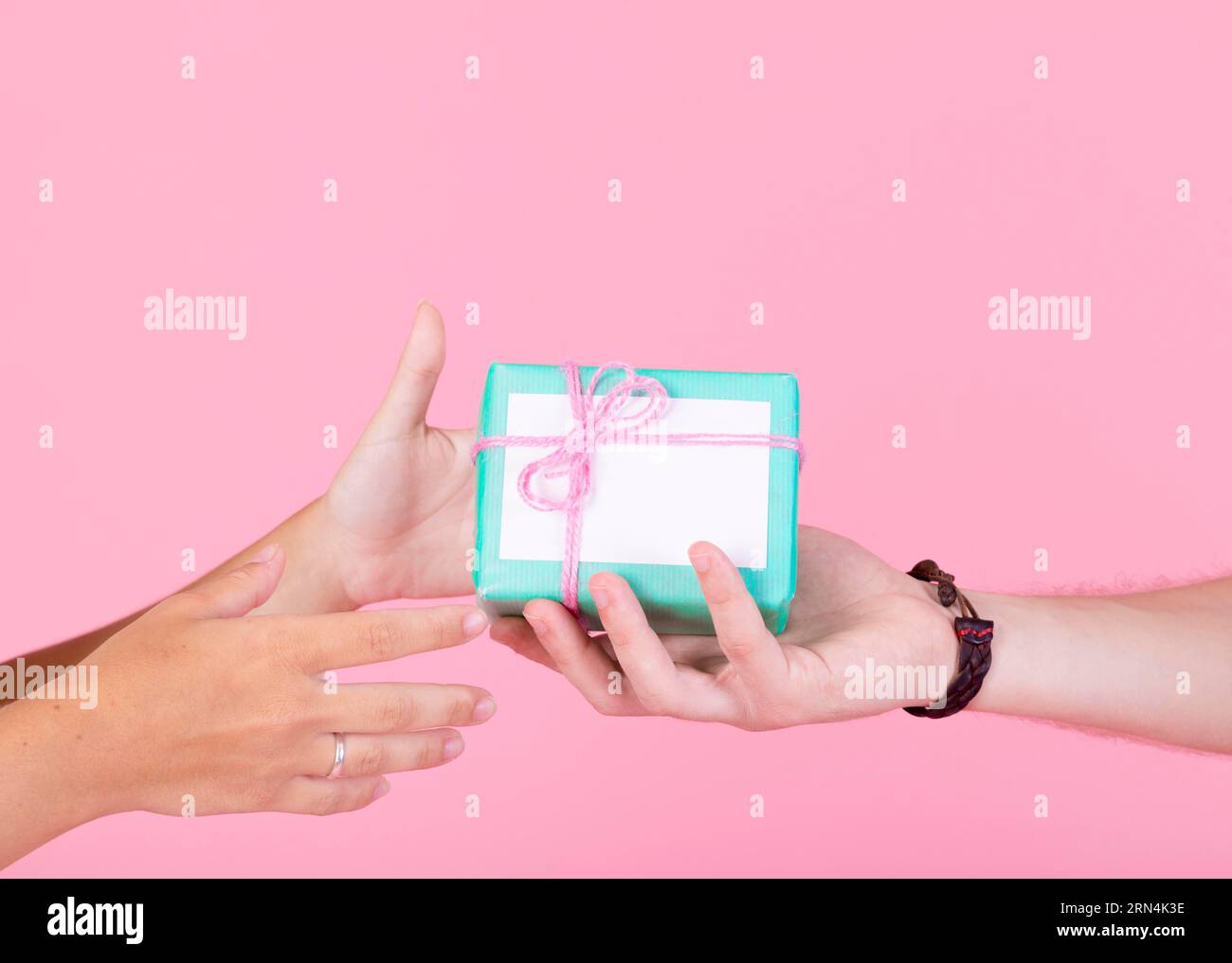 Man s hand giving gift box other person against pink background Stock ...