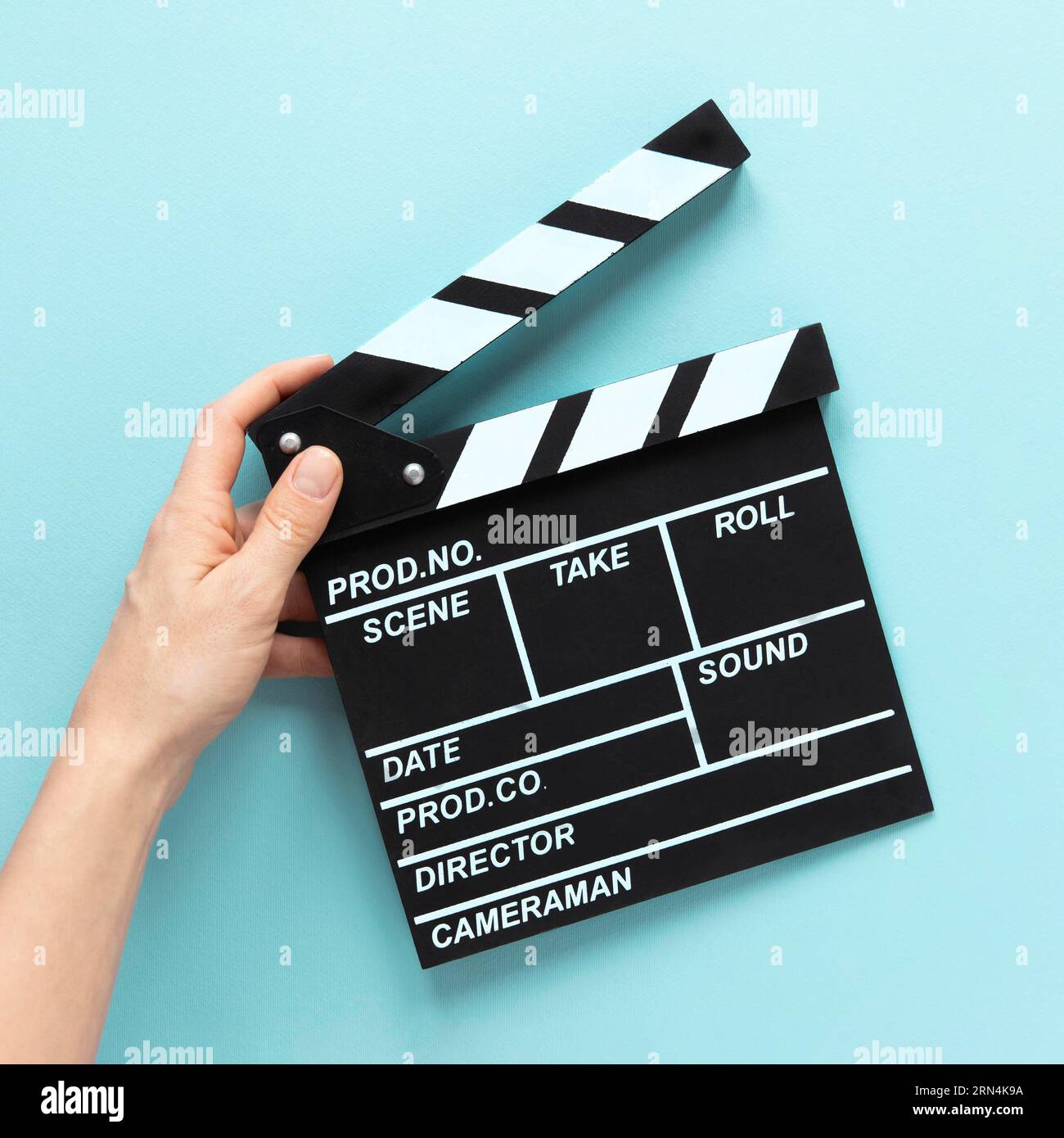 Person holding movie clapper blue background Stock Photo - Alamy