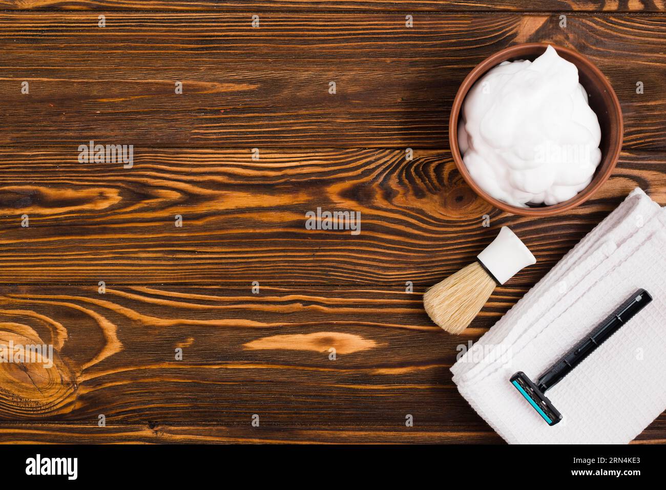 Overhead view foam bowl shaving brush razor white folded napkin against ...