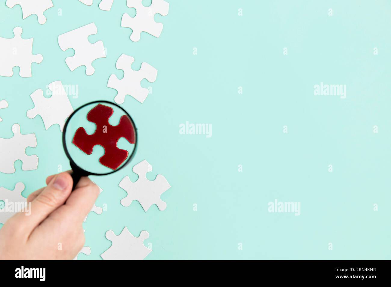Puzzle pieces with magnifier Stock Photo - Alamy