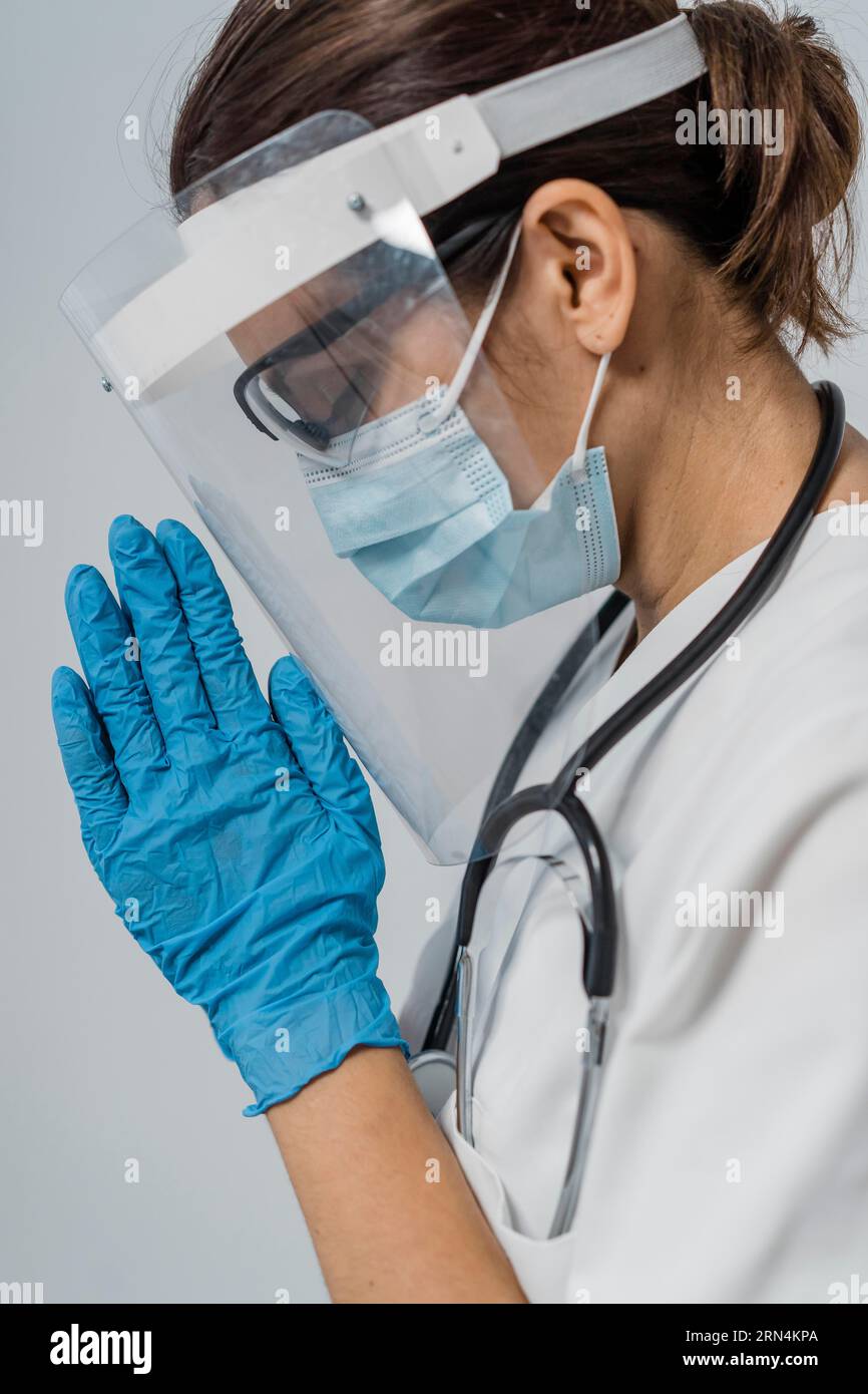 Side view female doctor with medical mask face shield praying Stock ...