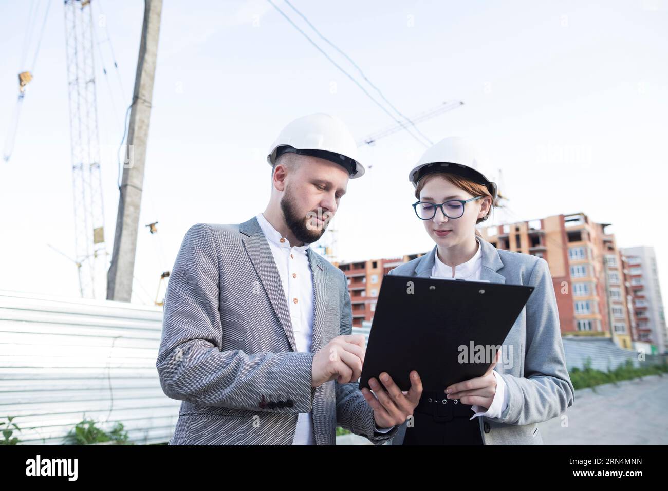 Young female male architect wearing hard hat looking clipboard Stock ...