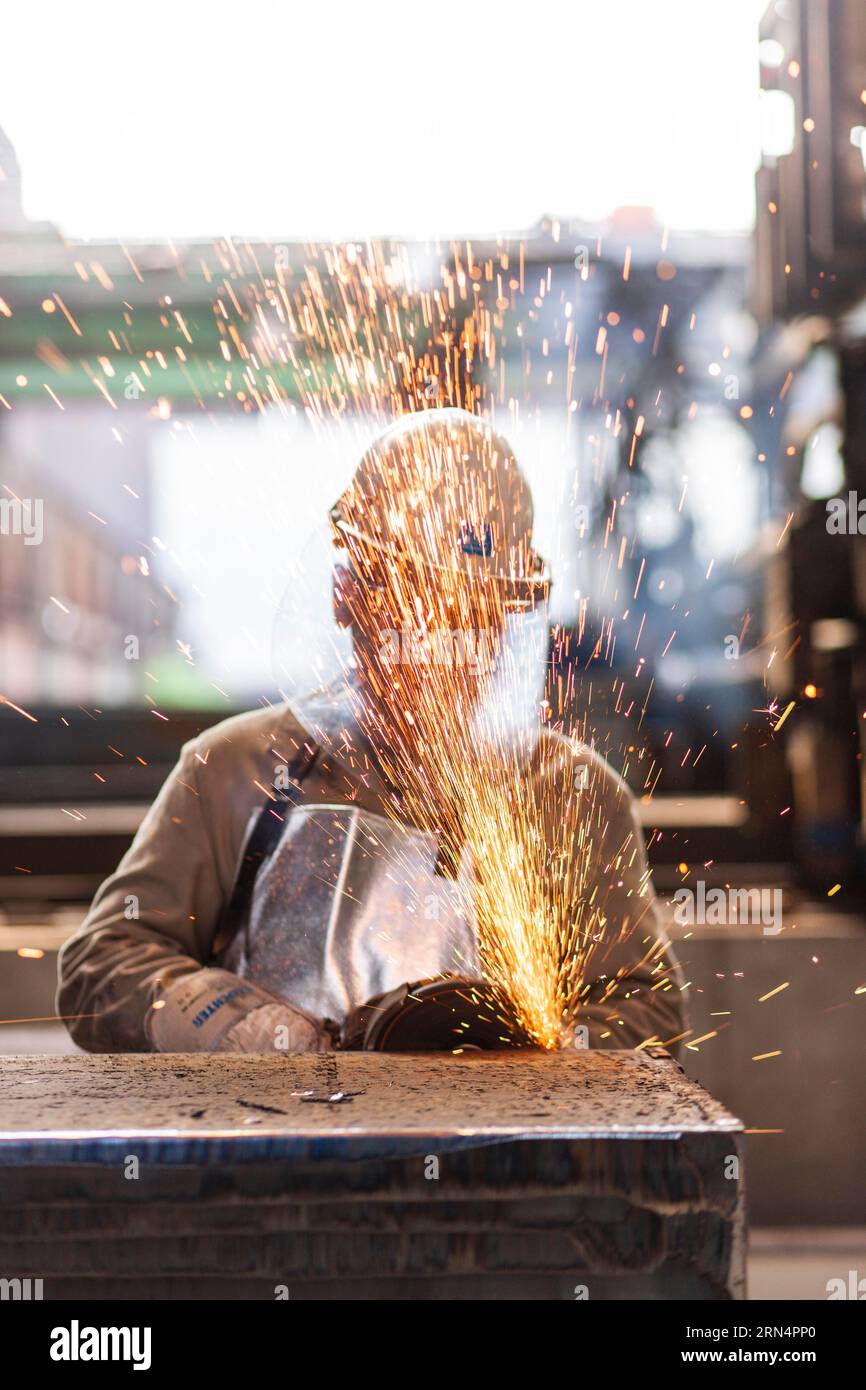 A worker grinds on a slab in a steel mill Stock Photo - Alamy