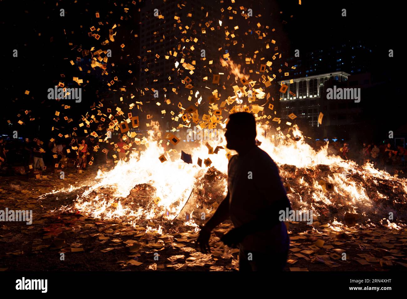 Ethnic Chinese throw paper offerings during burning of a giant paper ...