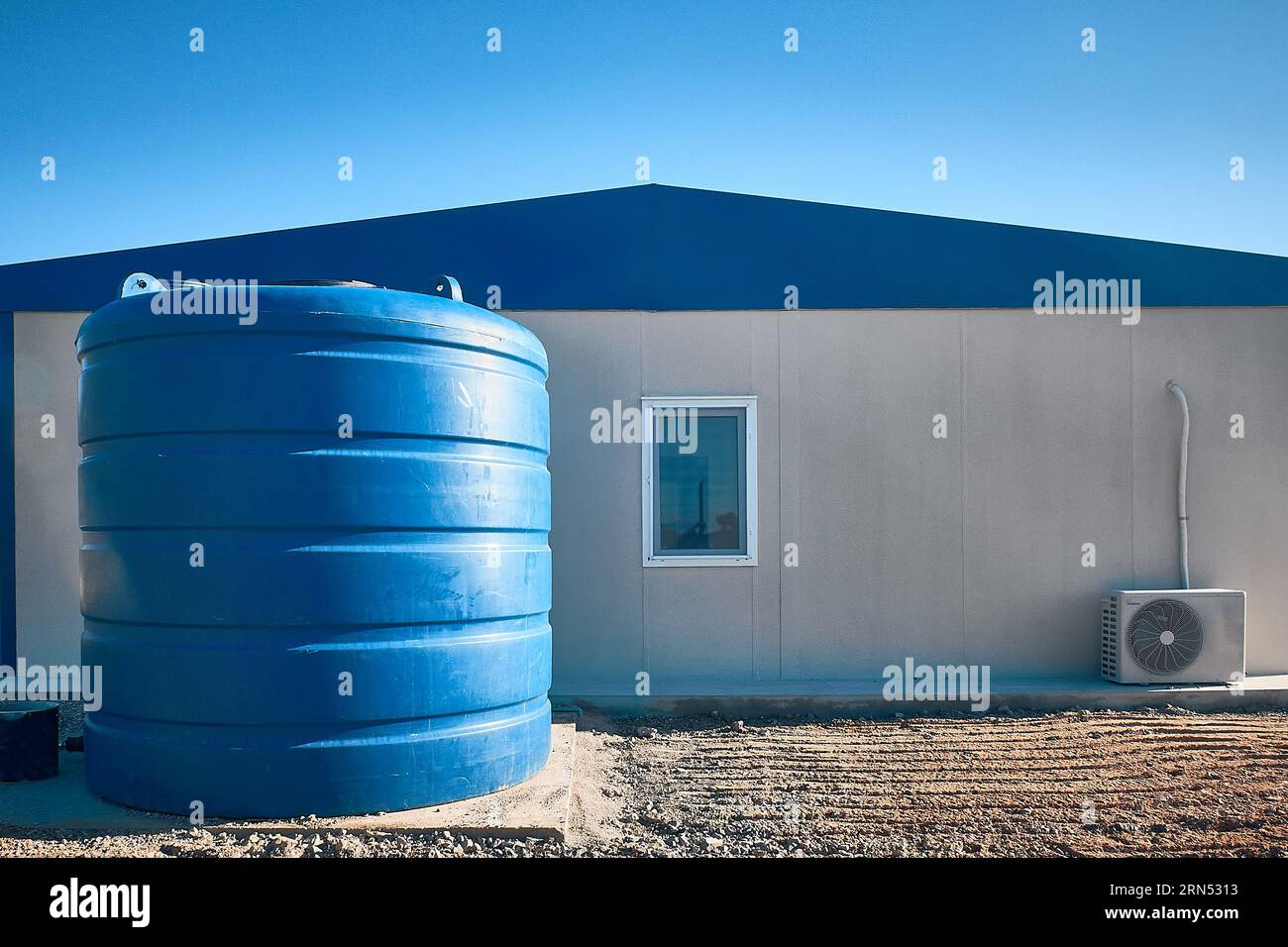 Blue plastic water tank stands next to prefabricated industrial ...