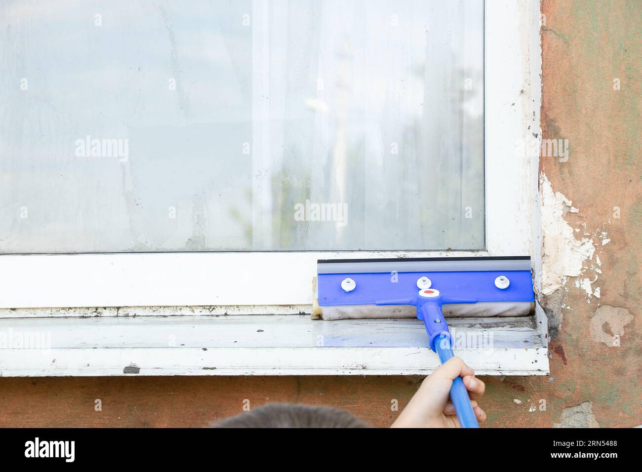 A child washes a dirty window with a mop from the street, wash windows ...