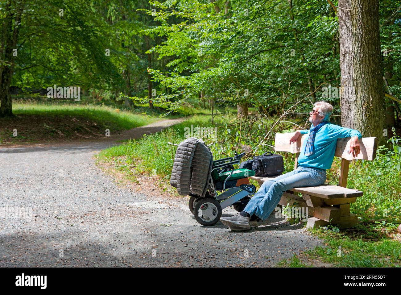 Disabled man sits on a bench in the forest and enjoys the sun Stock ...