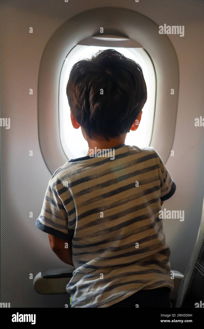 Child in the looking out the airplane window traveling on summer ...