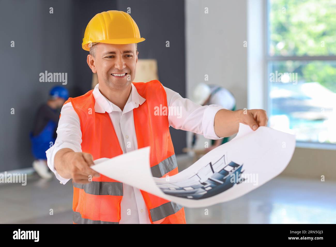 Mature builder with house plan working in room Stock Photo - Alamy