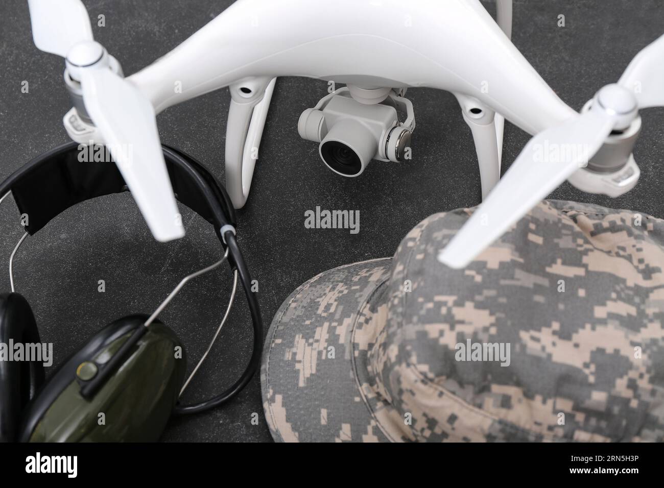 Modern quadcopter, military cap and headphones on black background ...