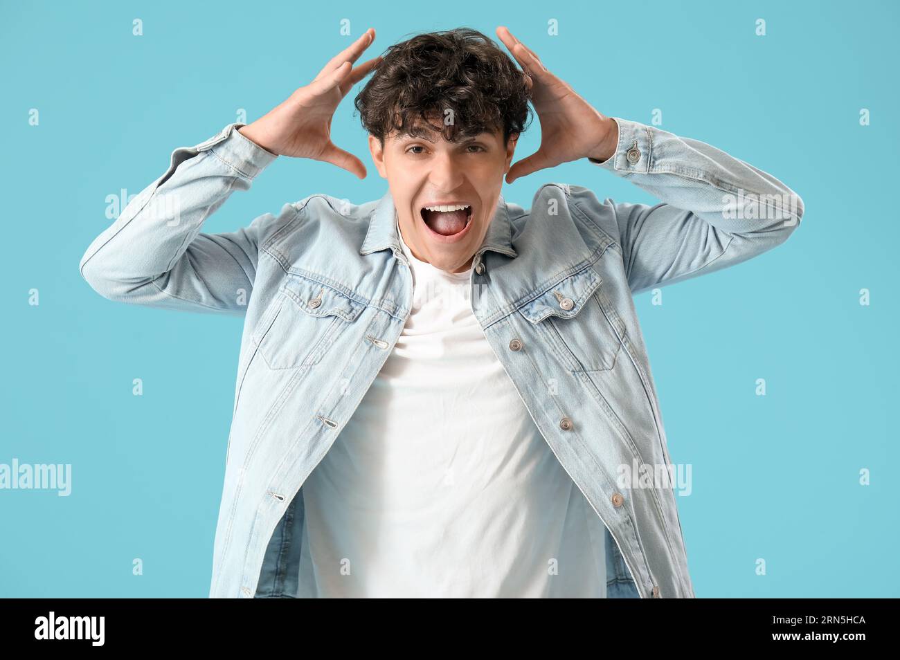 Portrait of angry yelling young man on blue background Stock Photo - Alamy