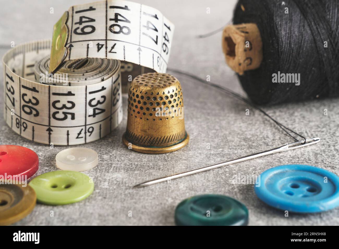 Sewing kit of needle, thimble, thread and measuring meter.On gray ...