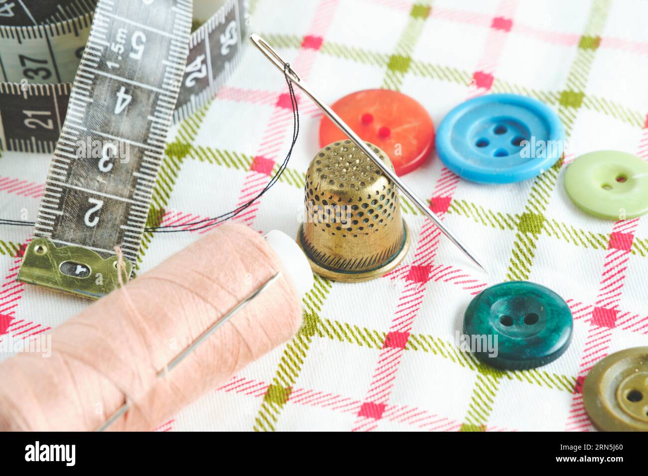 Sewing kit consisting needle, thimble, threads and measuring meter on a ...