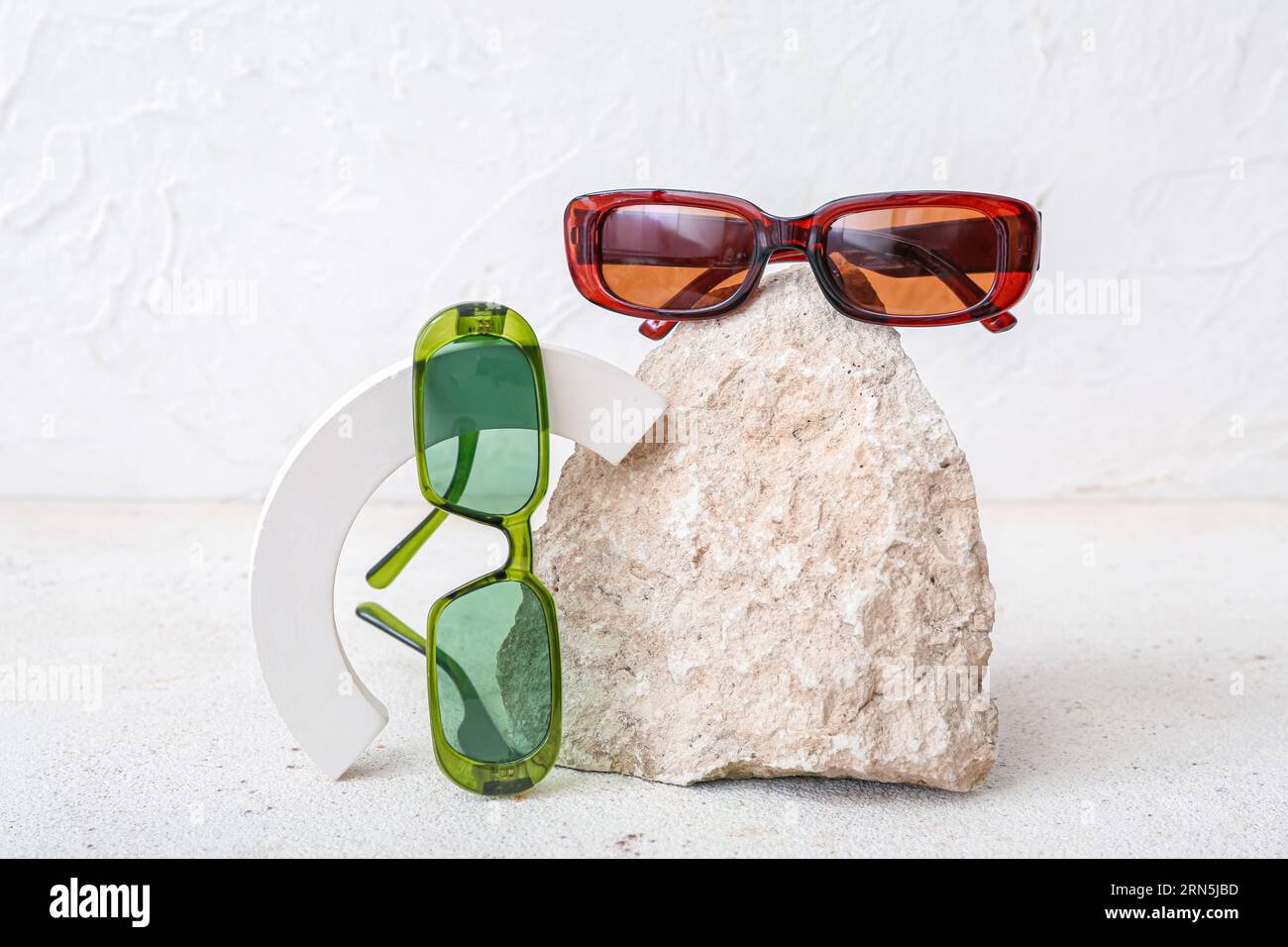 Decorative podium and stone with stylish sunglasses on white background ...