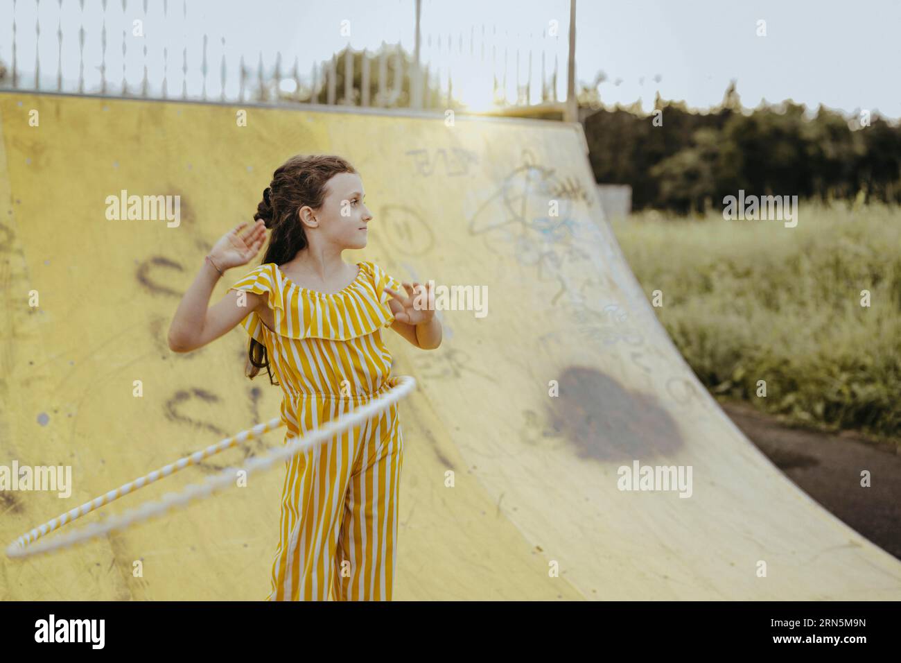 Girl, 9 years, in yellow and white striped jumpsuit does gymnastics ...