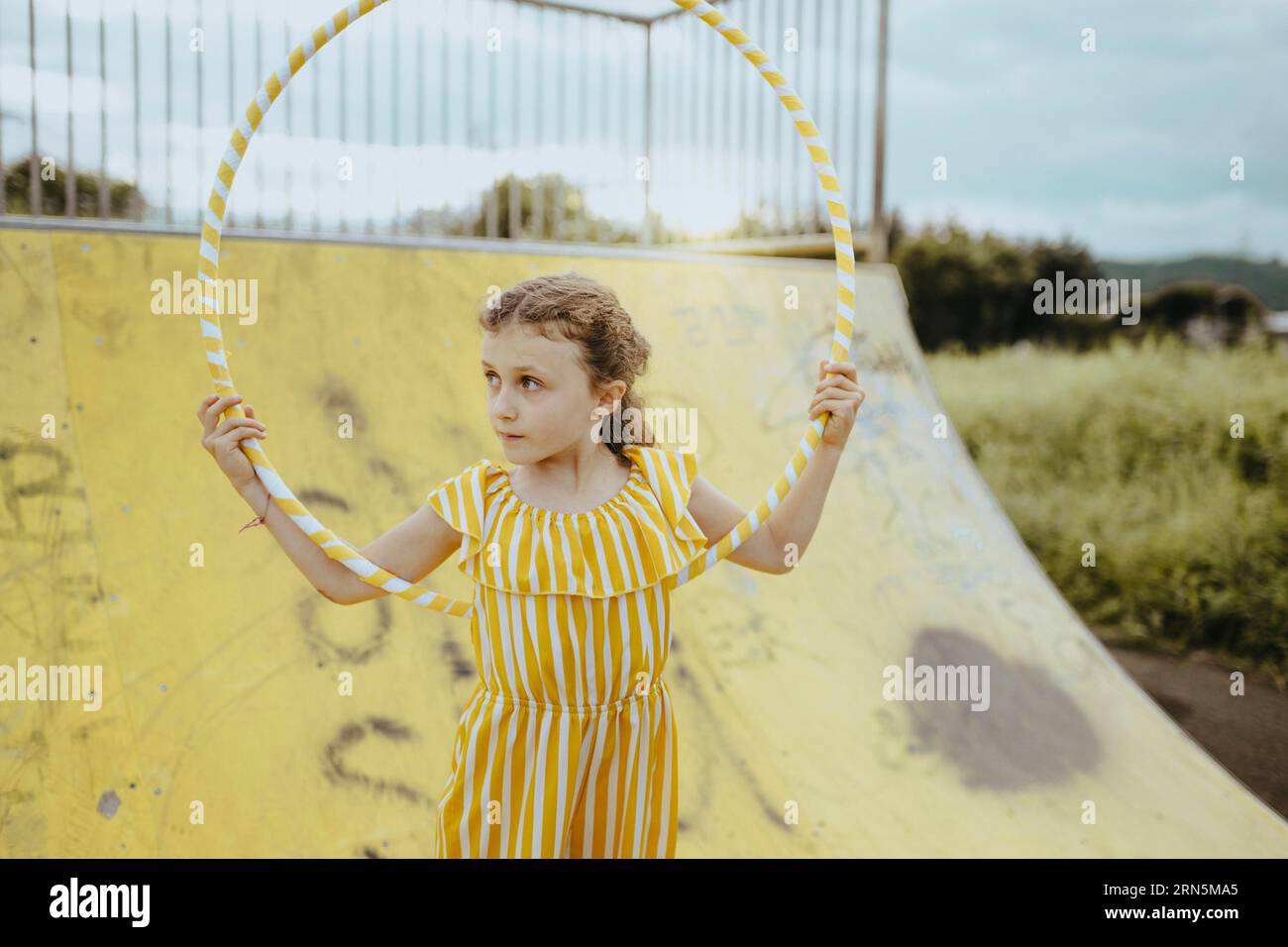 Girl, 9 years, in yellow and white striped jumpsuit does gymnastics ...
