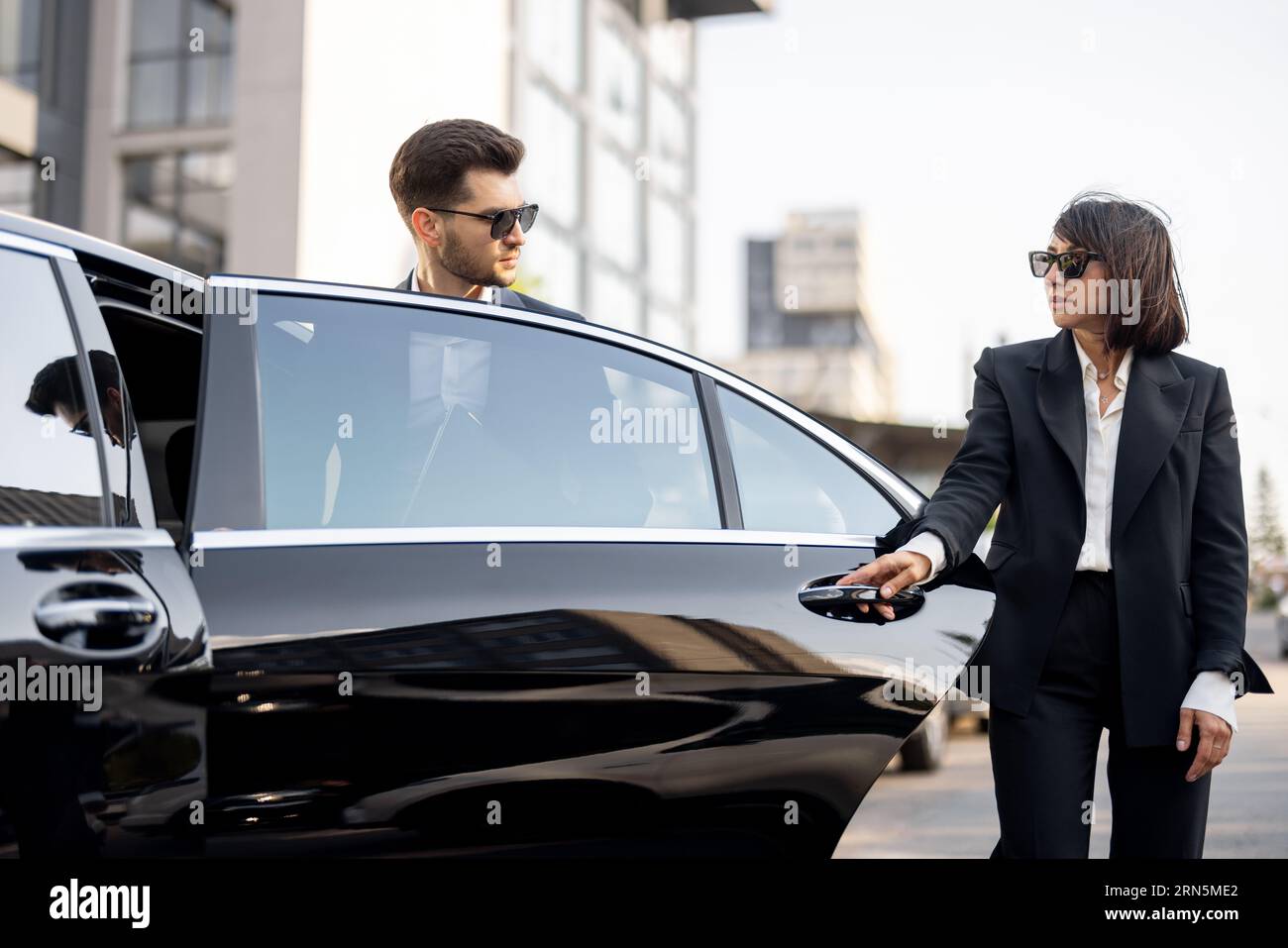 Female chauffeur helps a business man to get out of the car Stock Photo ...