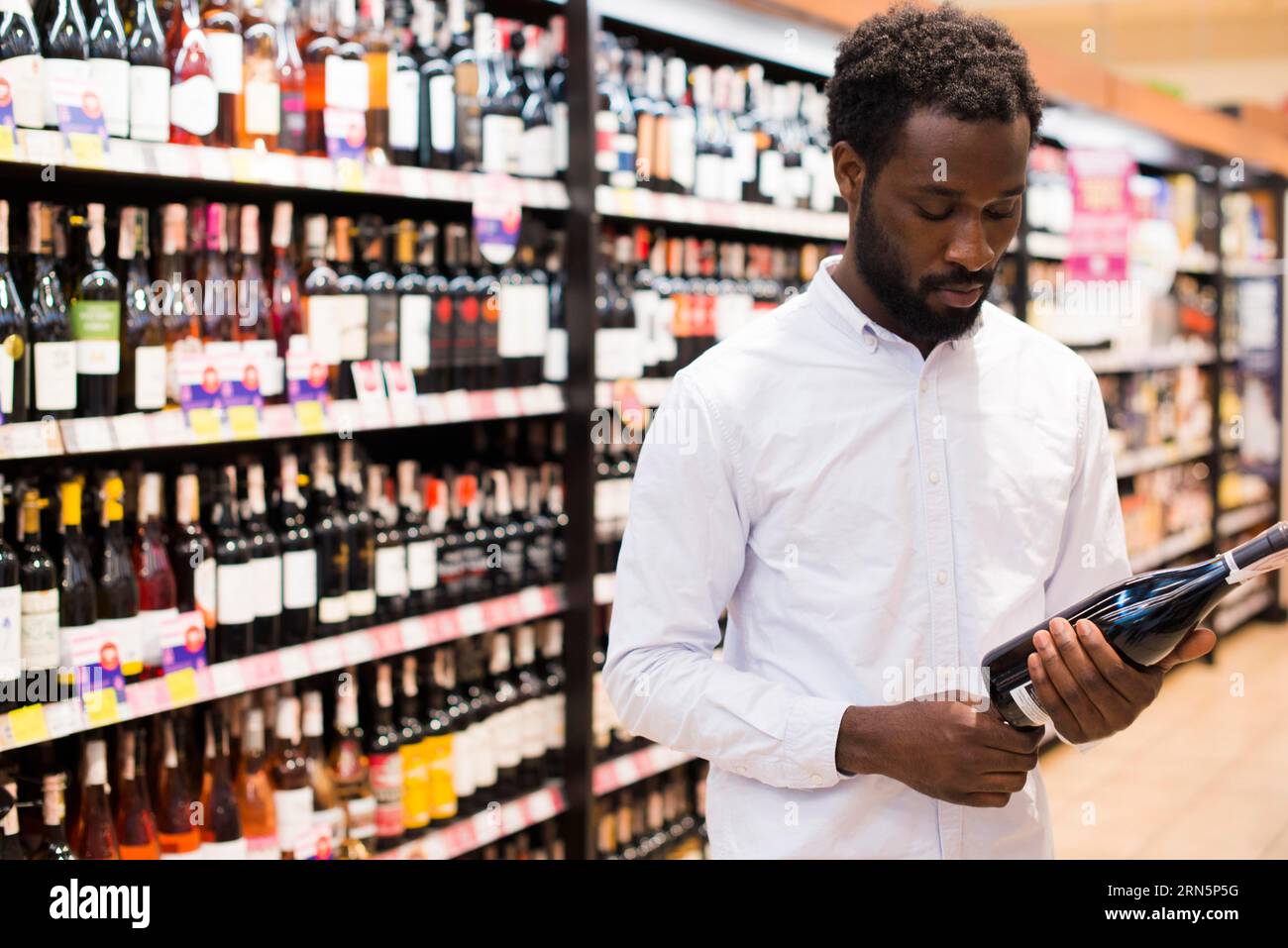 Man choosing bottle wine alcohol section Stock Photo - Alamy