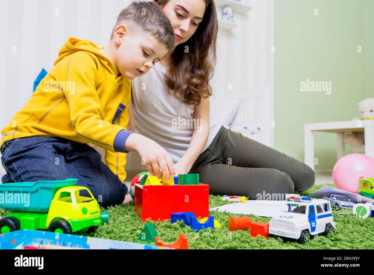 Boy playing toys with woman Stock Photo - Alamy