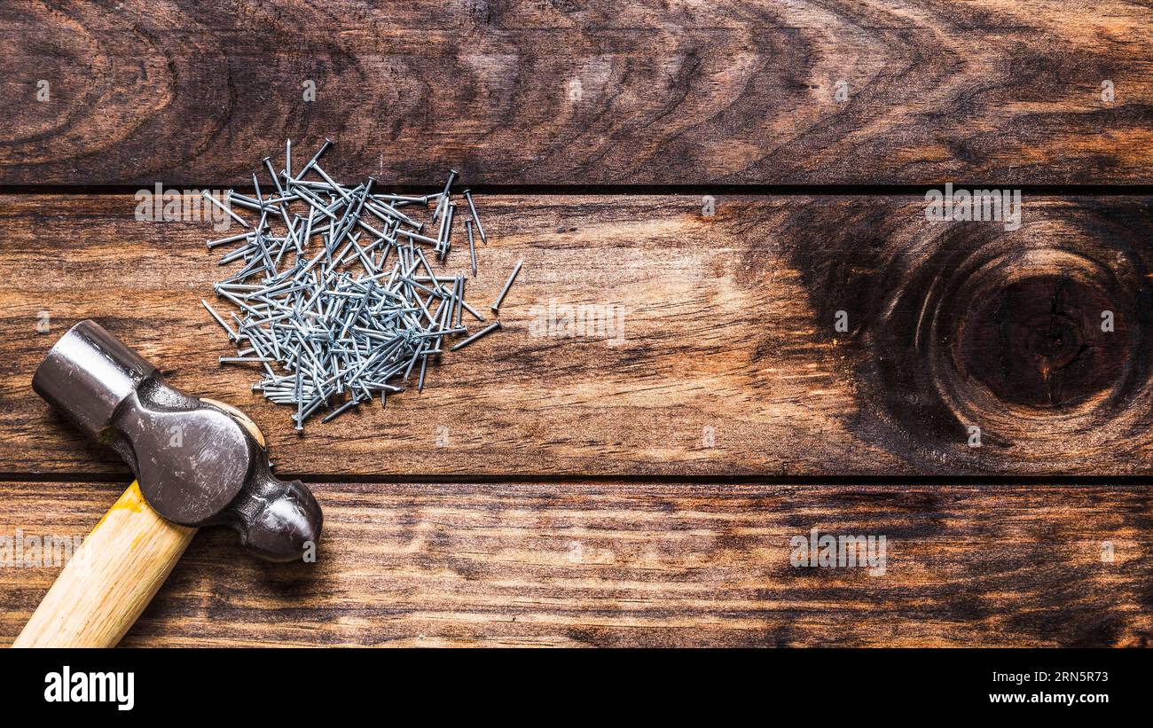 Elevated view hammer with many bolts wooden background Stock Photo - Alamy