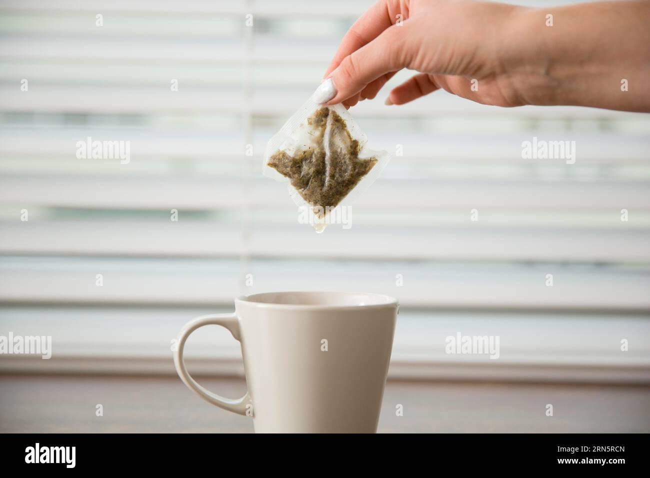 Hand holding tea bag Stock Photo - Alamy