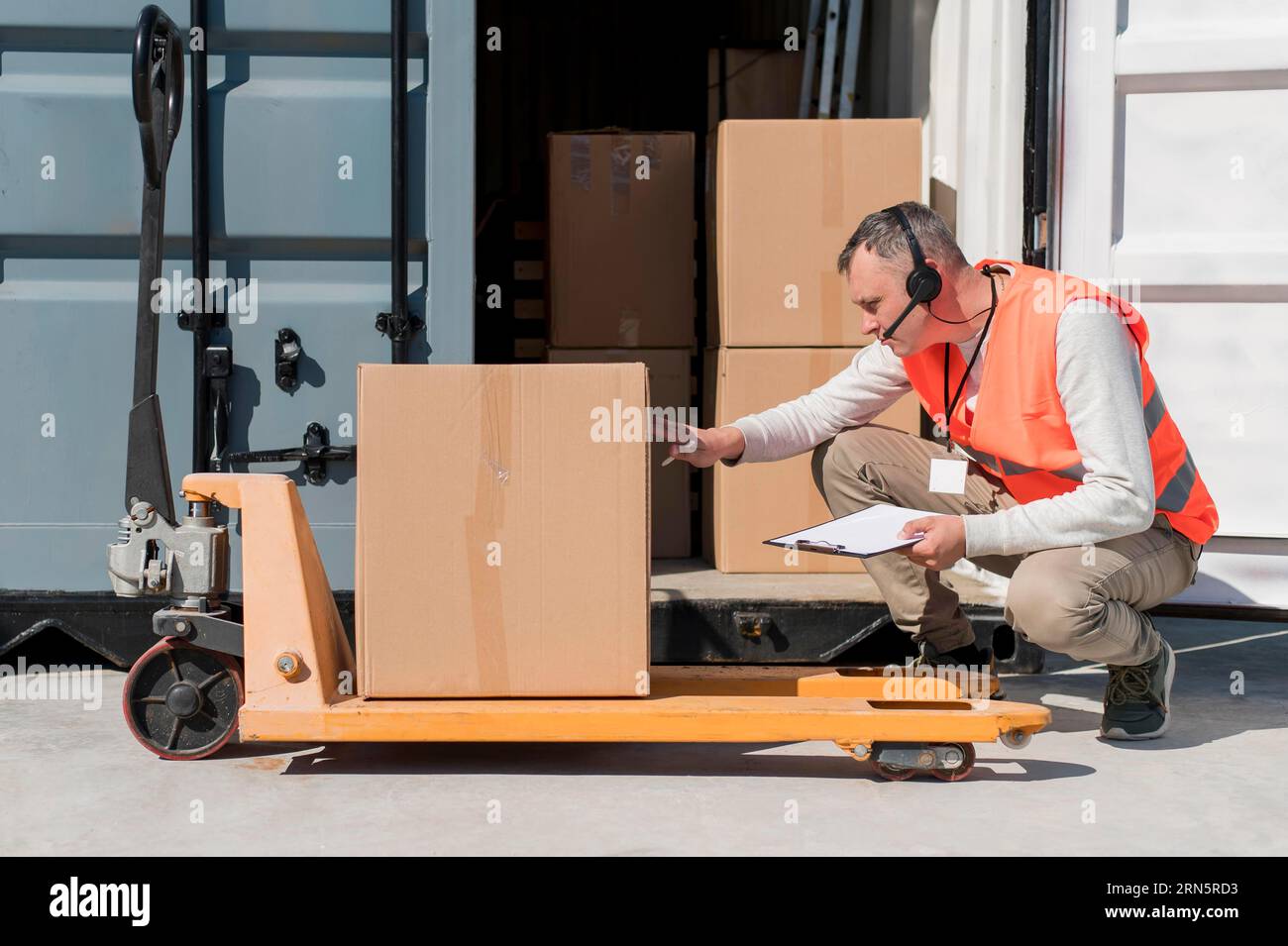Full shot man with pallet truck Stock Photo - Alamy
