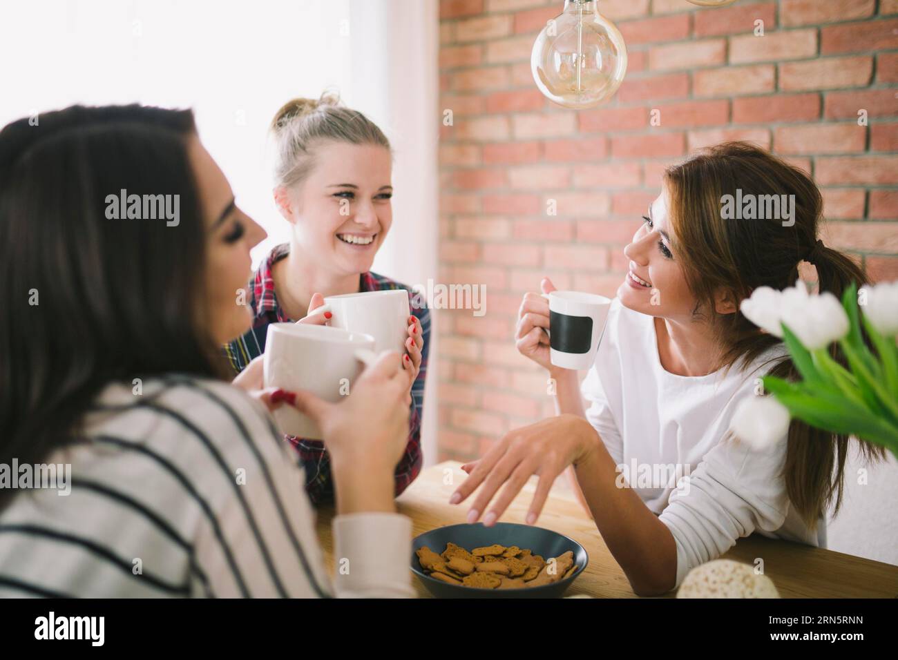 Laughing girls drinking tea talking Stock Photo - Alamy