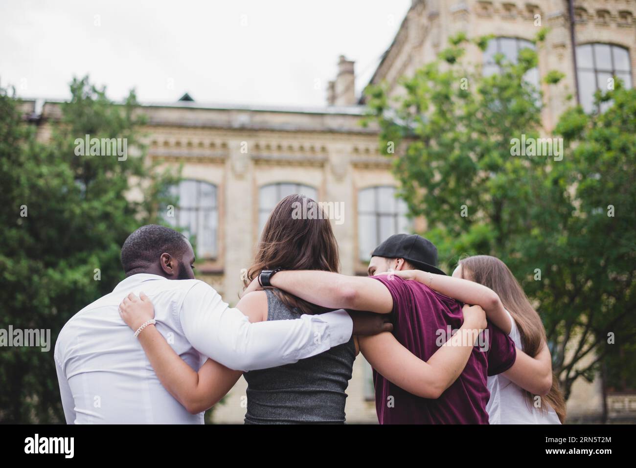 People standing together hugging Stock Photo - Alamy